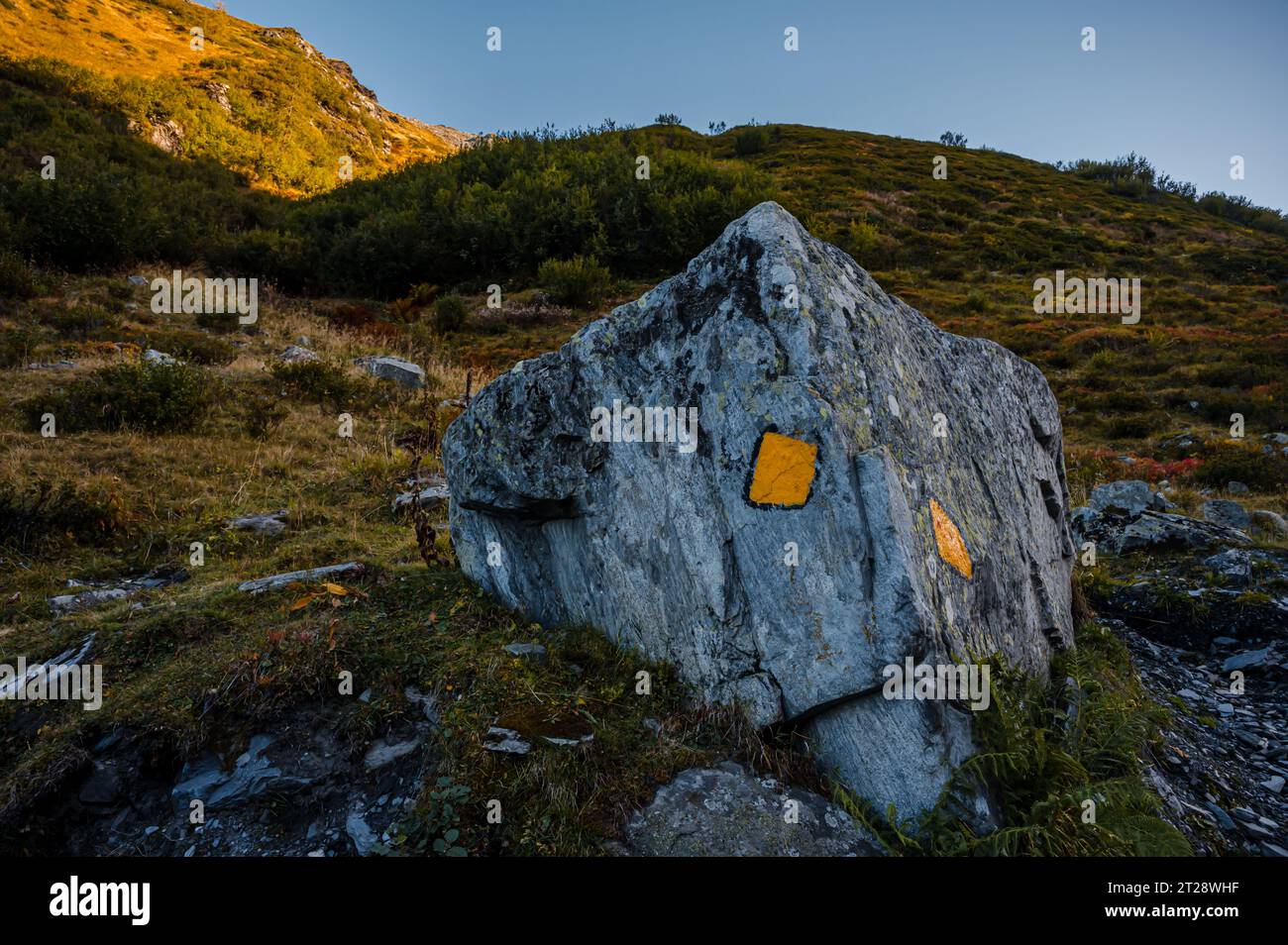 Hiking sign on rock. Yellow sign for swiss hiking trails in Switzerland ...