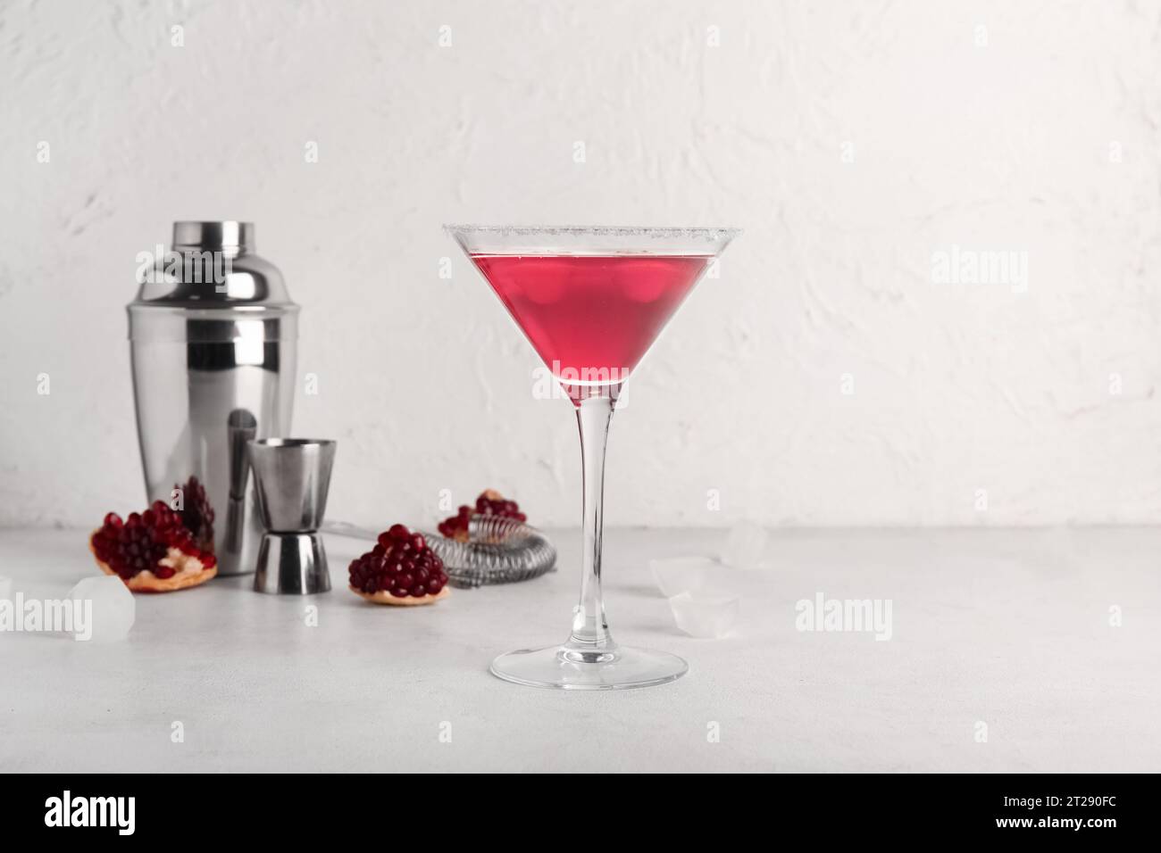 Glass of Cosmopolitan cocktail with pomegranate and shaker on white ...