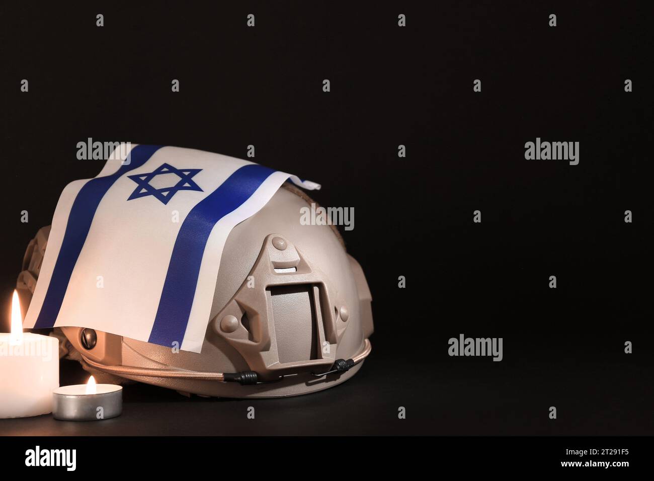 Military helmet with flag of Israel and burning candles on dark ...