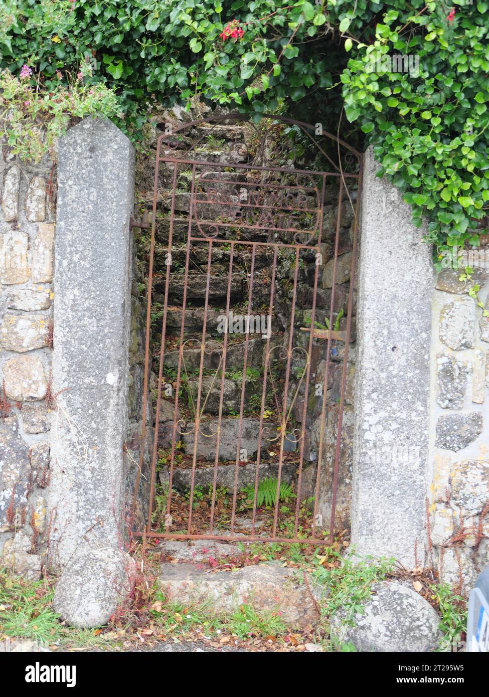 Rusty gate with steps leading to a garden in Mousehole in Cornwall ...