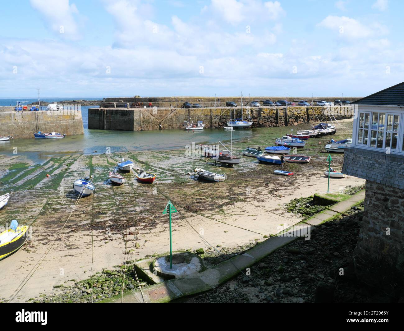 Colorful fishing boats lie on the sandy bottom in front of the pier of ...