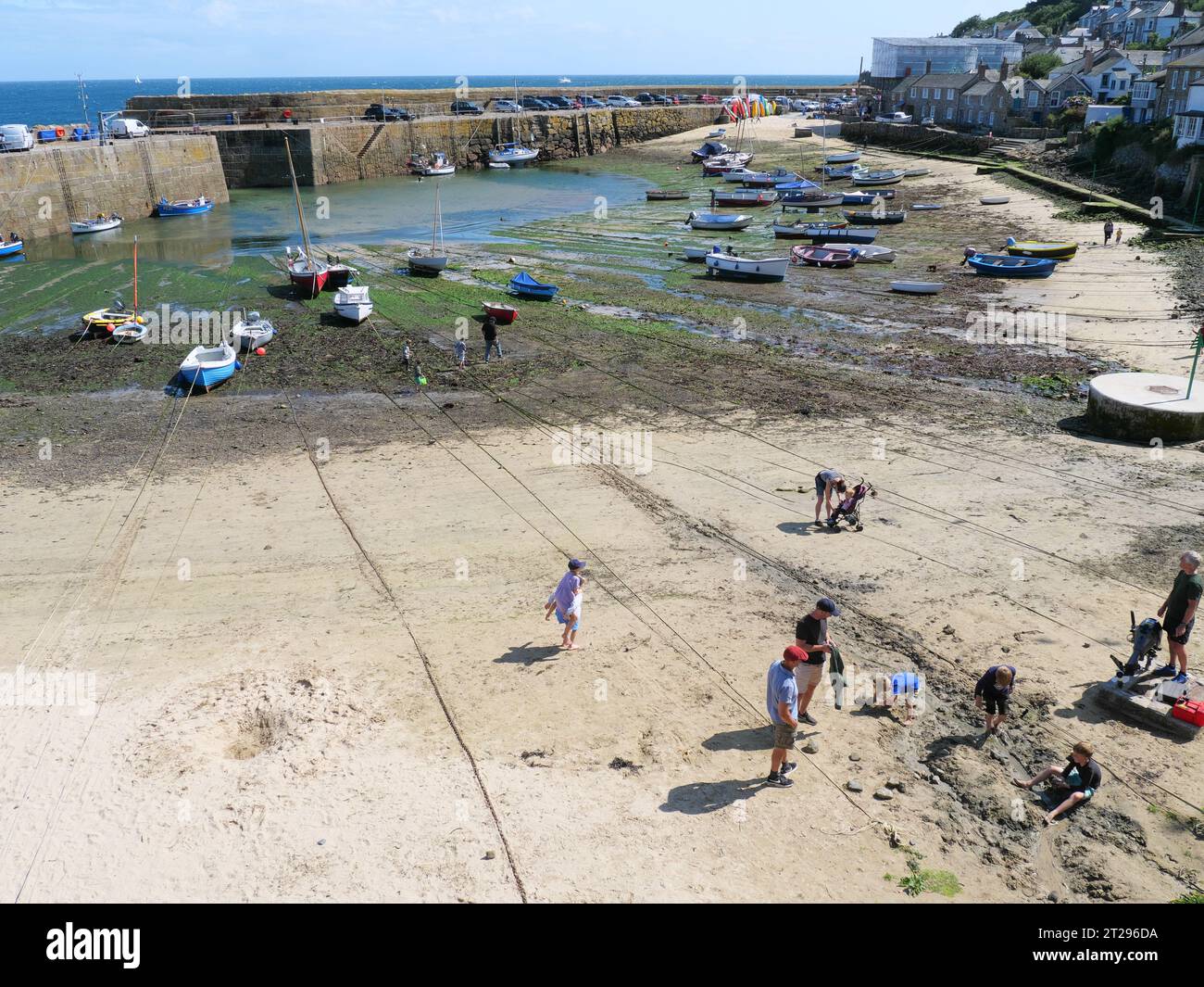 Colorful fishing boats lie on the sandy bottom in front of the pier of ...
