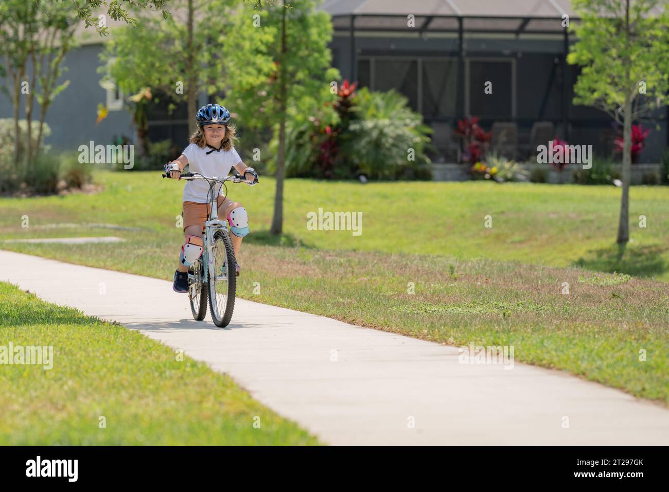 Cute kid riding a bike in summer park. Children learning to drive a ...