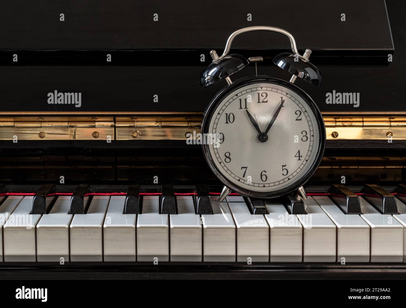 Black alarm clock stand on the Piano Keyboard. Time for music concept ...