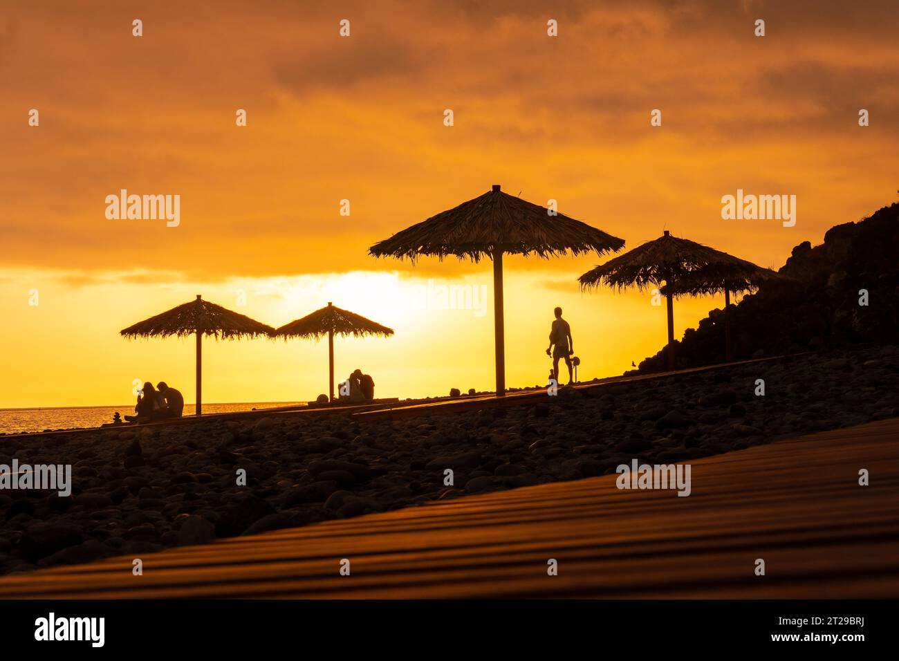 Orange sunset on the umbrellas at Ponta do Sol beach, Madeira. Portugal ...