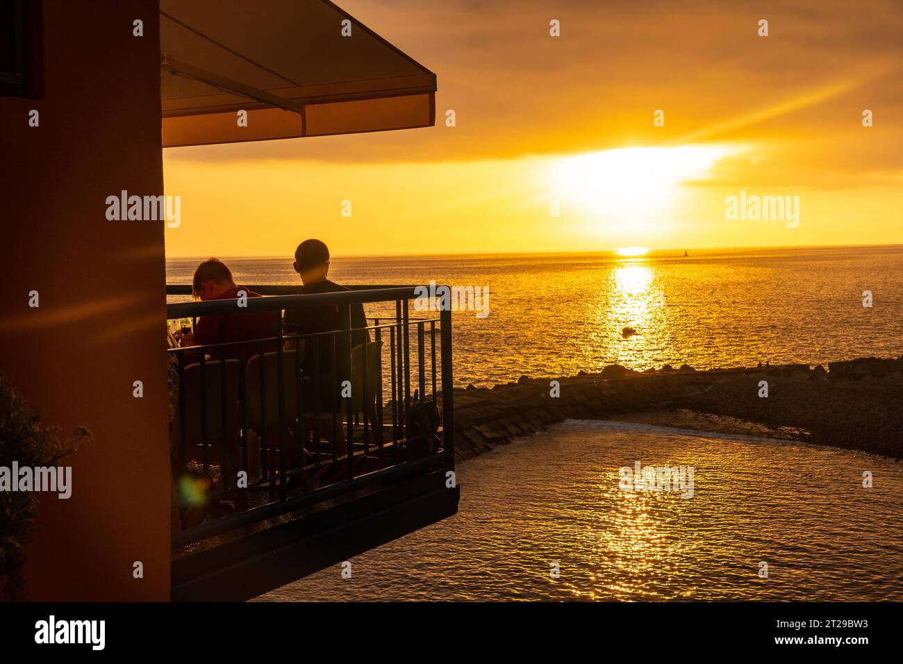 Sunset in Ponta do Sol, Madeira, a family having dinner on the beach in ...