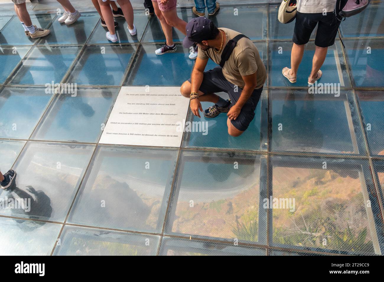 A tourist on the glass floor at the highest viewpoint called Cabo Girao ...