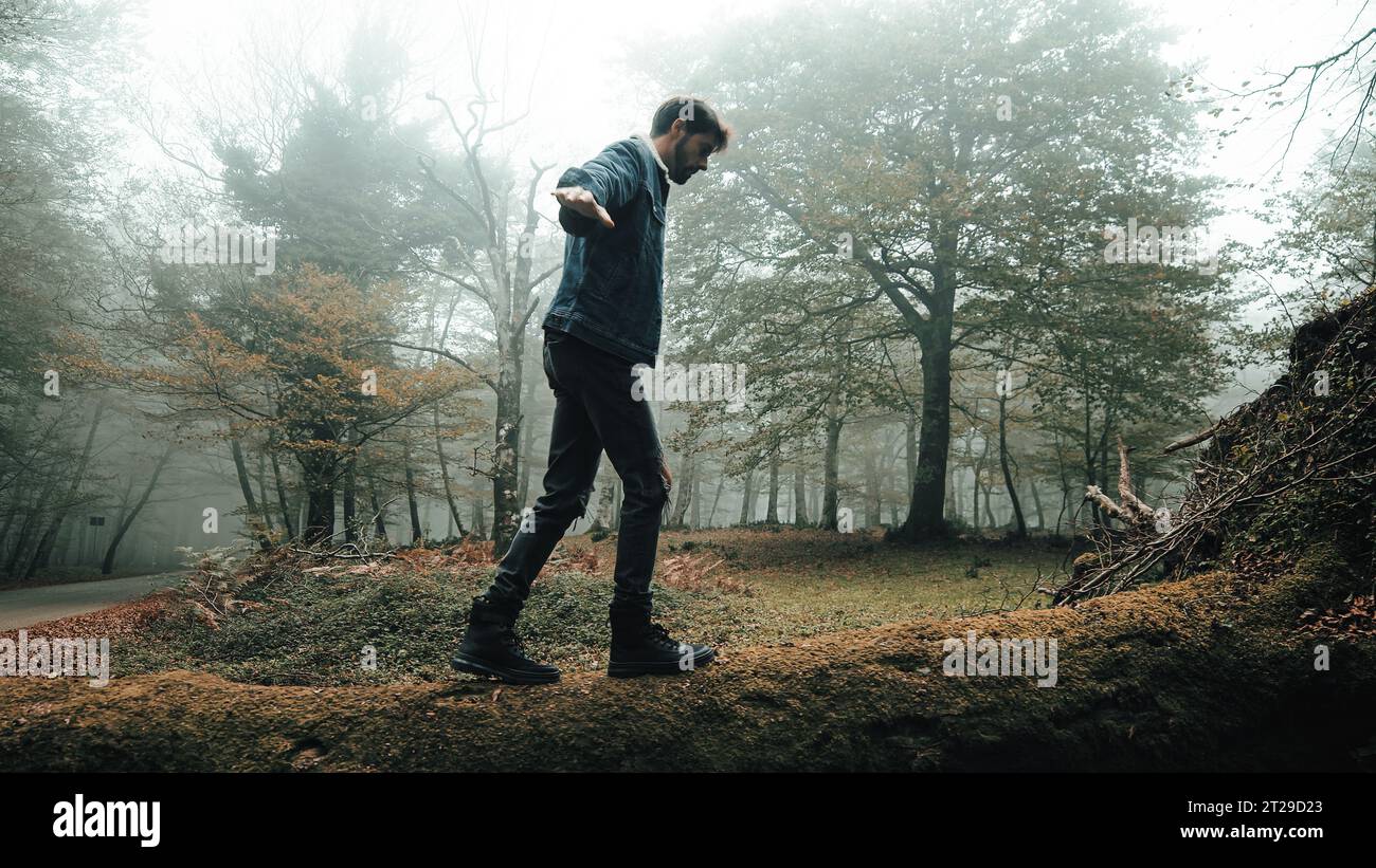 Man walks poised on a tree trunk Stock Photo - Alamy