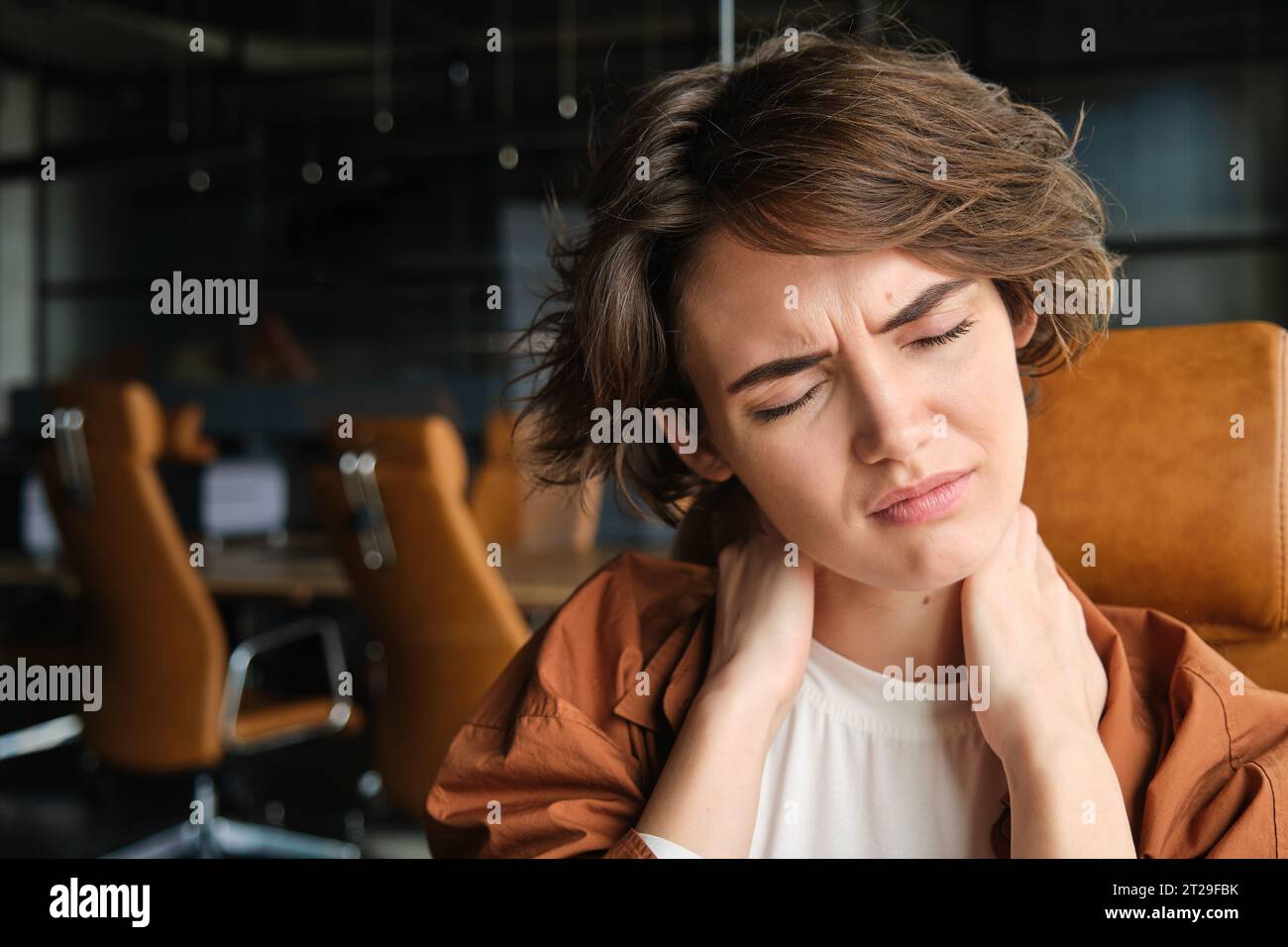 Close up portrait of female employee, manager touches her neck and ...
