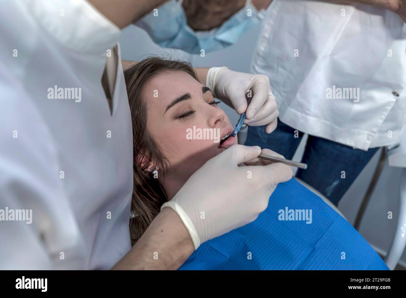 A female dentist treats a patient's teeth. The dentist makes a ...