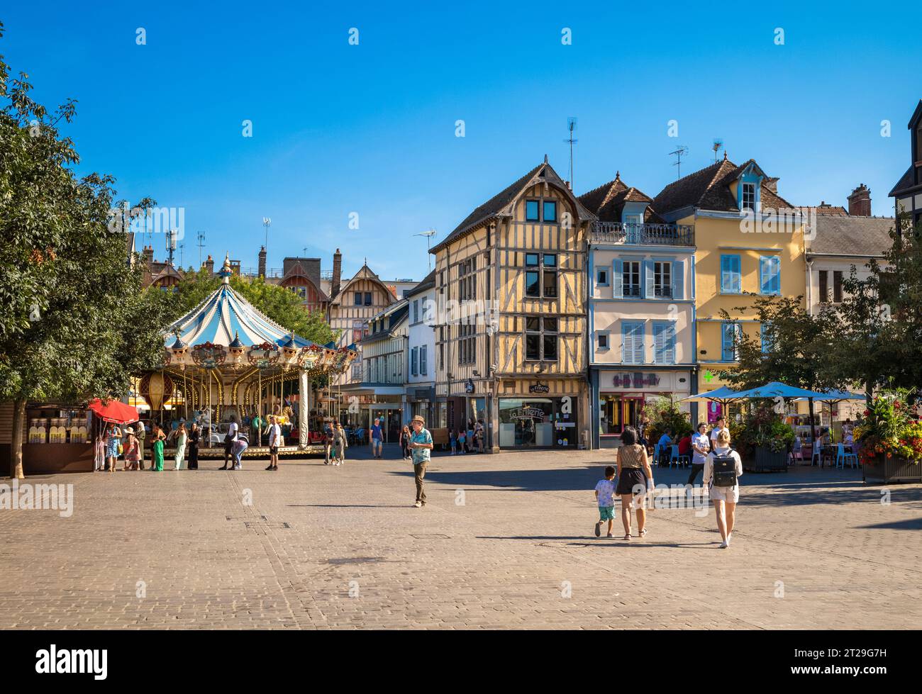 People walk in Pl. Alexandre Israel next to the Modern Times Carousel ...