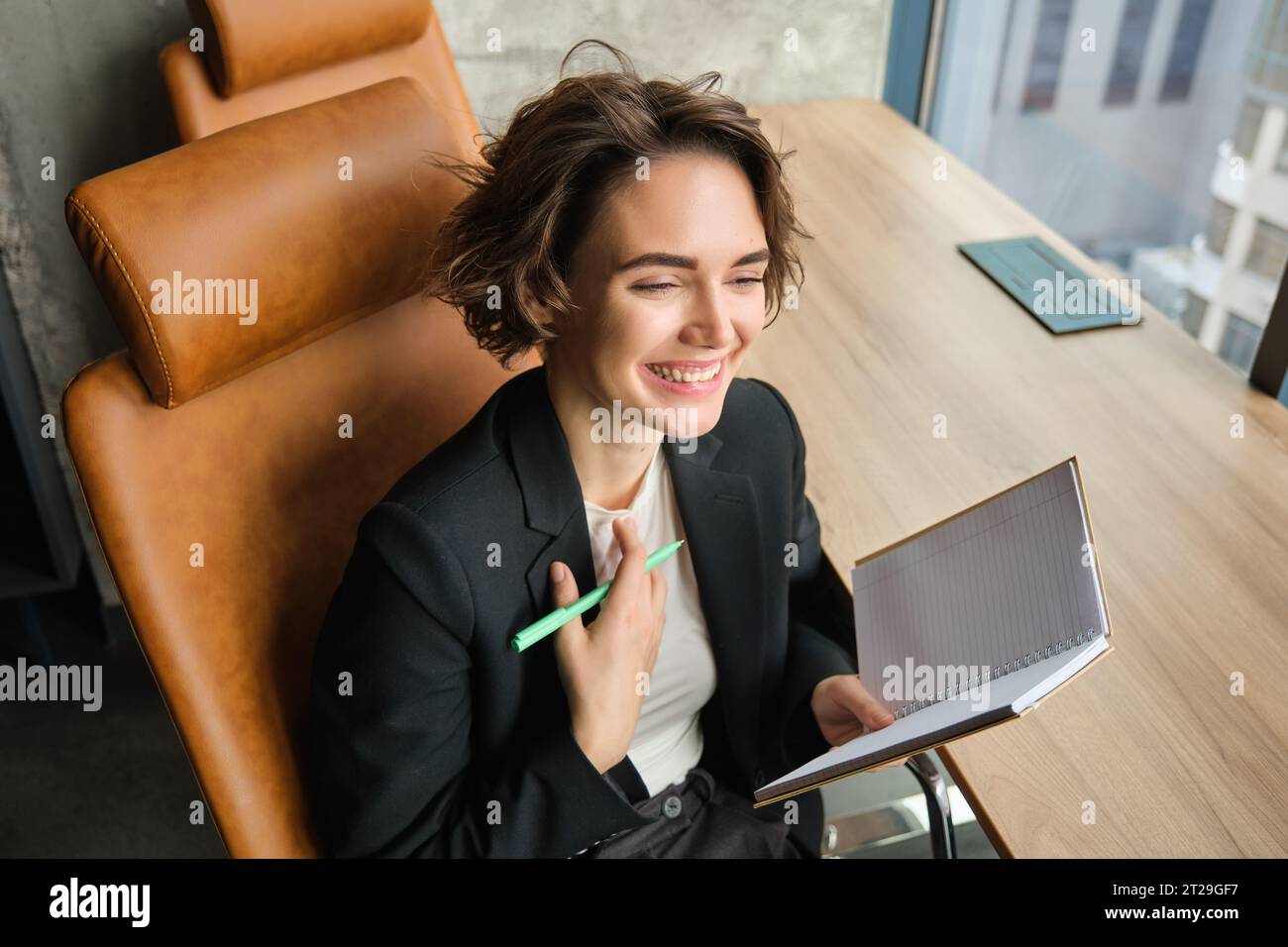 Corporate woman with pen and notebook, making notes, writing down in ...