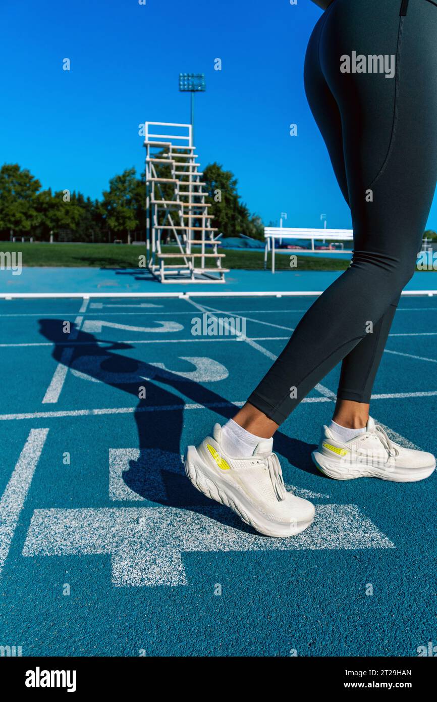 Shadow cast on a blue running track of a tanned young female runner ...