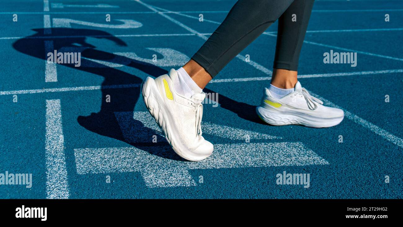 Detail of legs and sports shoes of a young female runner, prepared in a ...