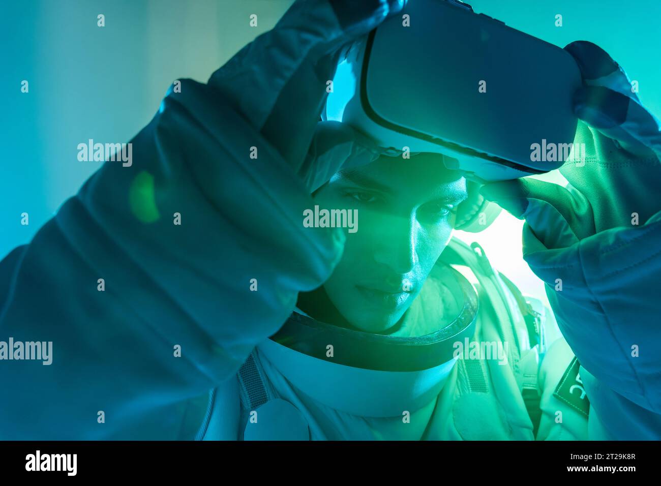 Male astronaut in spacesuit touching virtual reality goggles over head ...