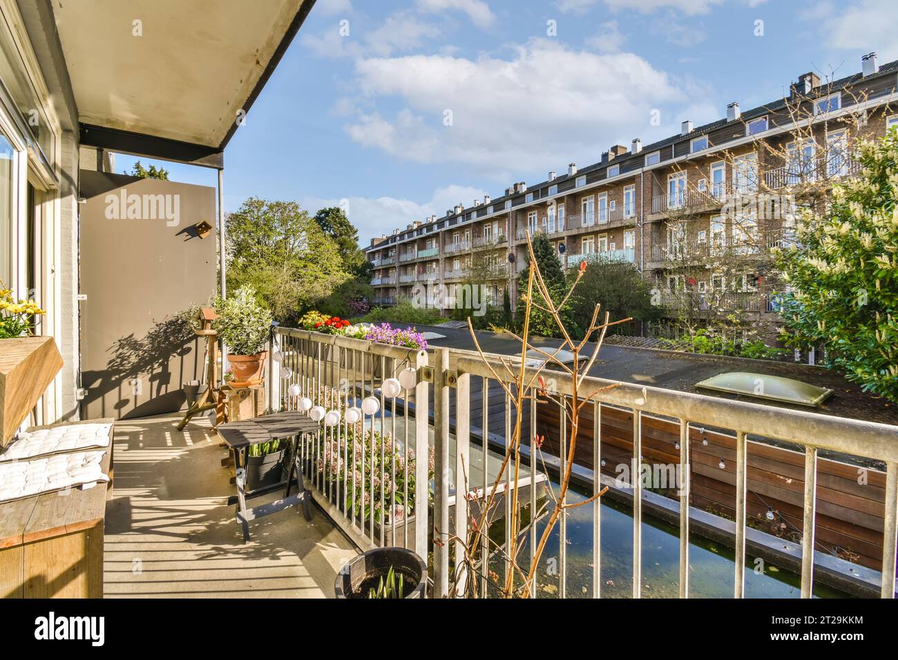 Balcony with plants and table and flowers on railing with buildings in ...