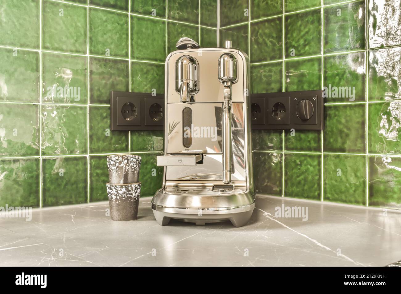 Stainless steel coffee maker with cups placed on counter in front of ...
