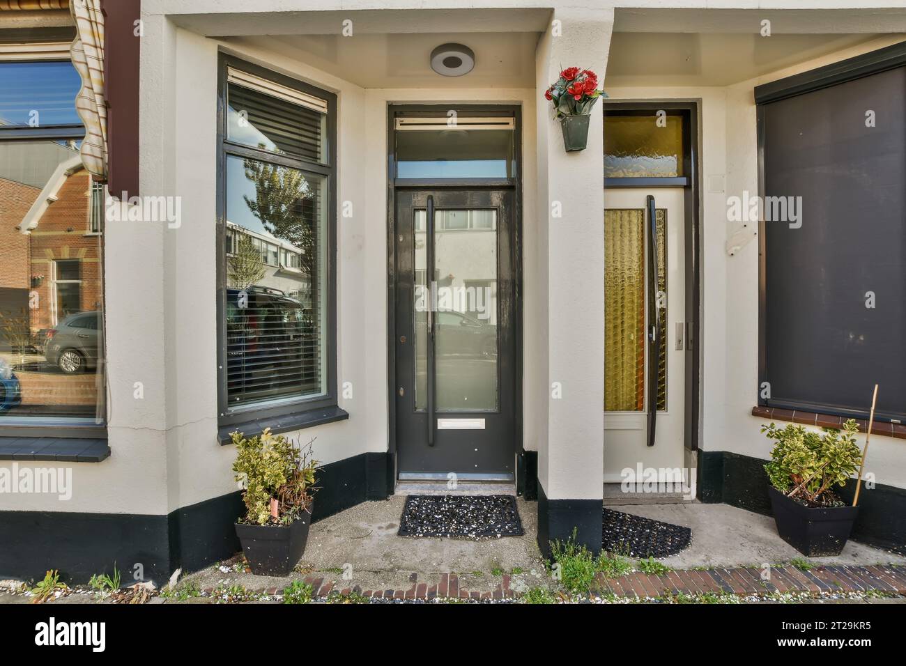 Facade of contemporary house with closed front doors and potted plants ...
