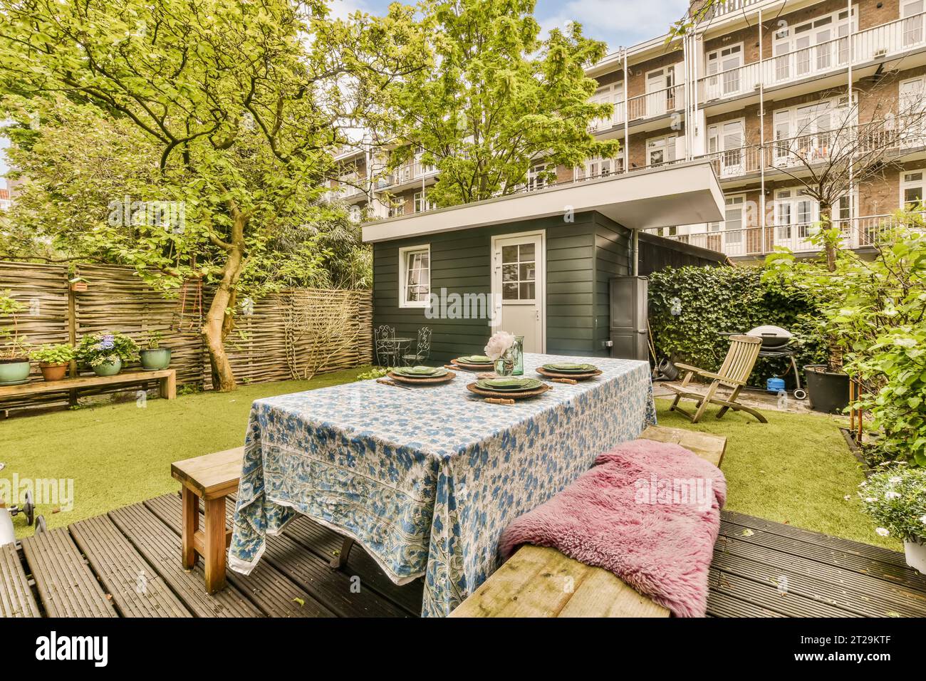 Backyard area with shed and furniture by small garden with apartment ...