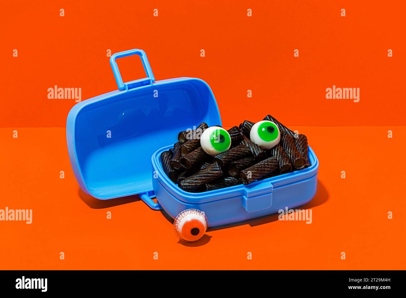 Horror lunch with black pasta and eyes in lunchbox placed on orange ...