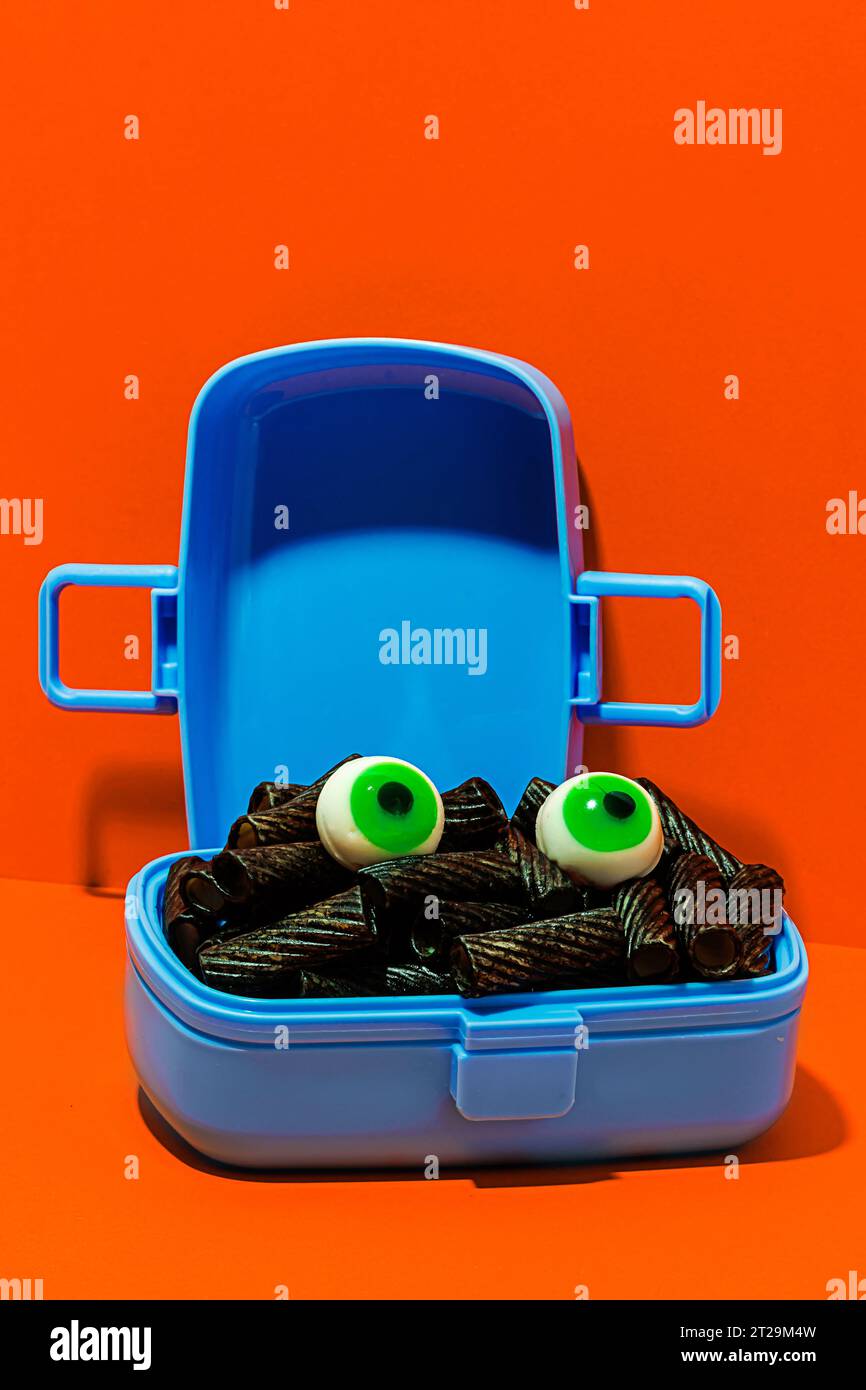 Horror lunch with black pasta and eyes in lunchbox placed on orange ...
