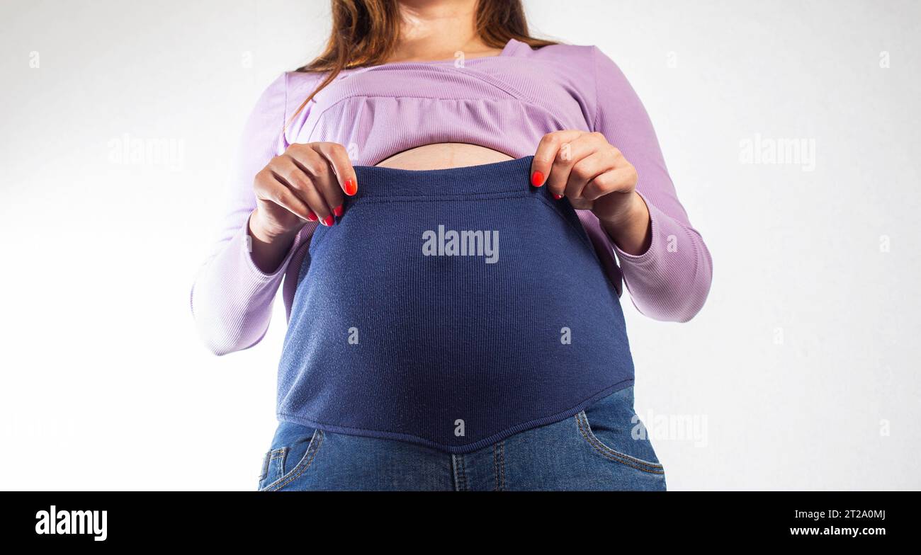 Pregnant girl with a big belly in jeans on a white background. The ...