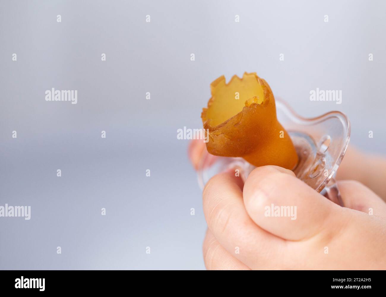 A baby's pacifier is chewed and torn in a baby's hand, close-up ...