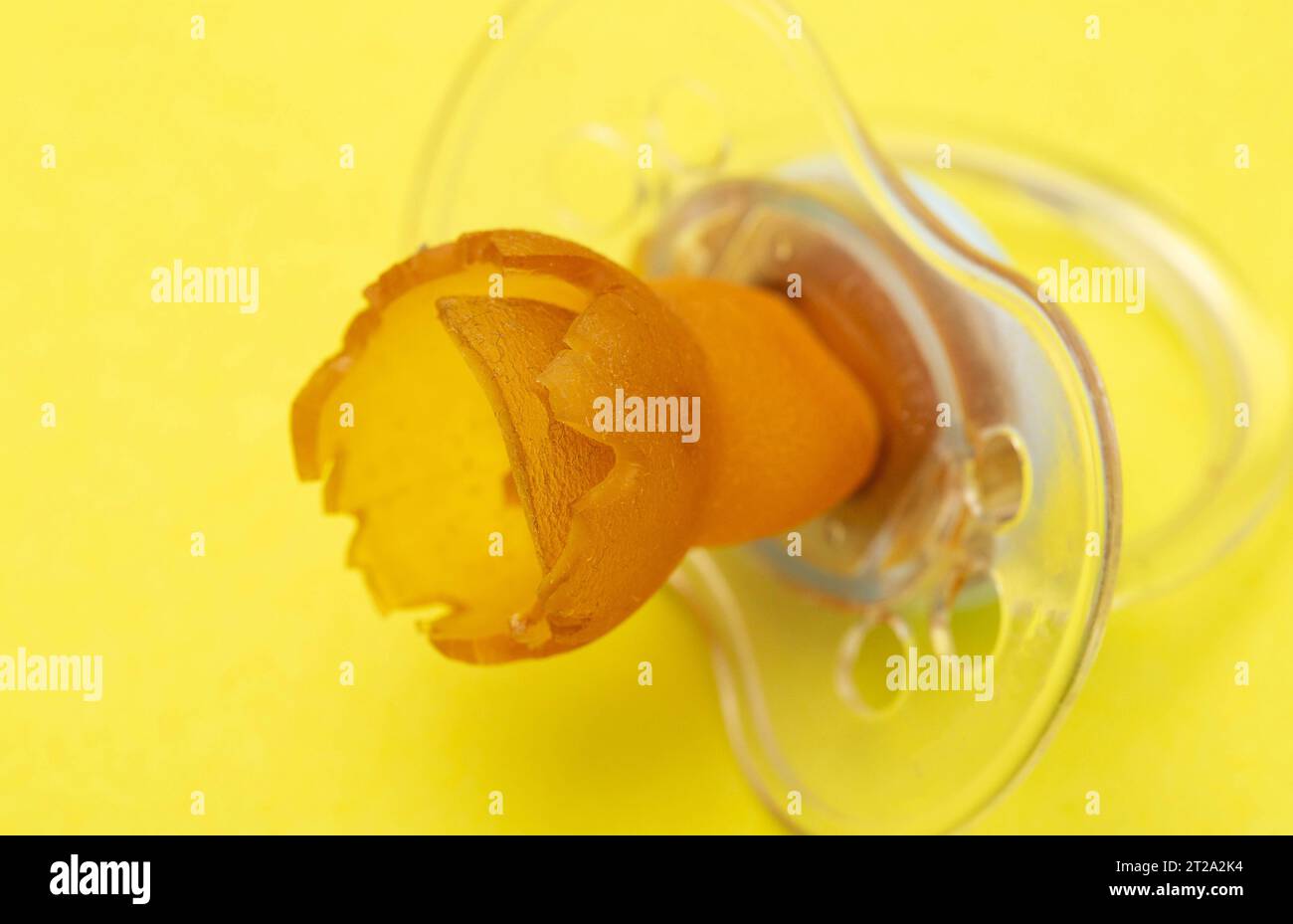 A chewed baby pacifier on a yellow background. Concept of teething in ...