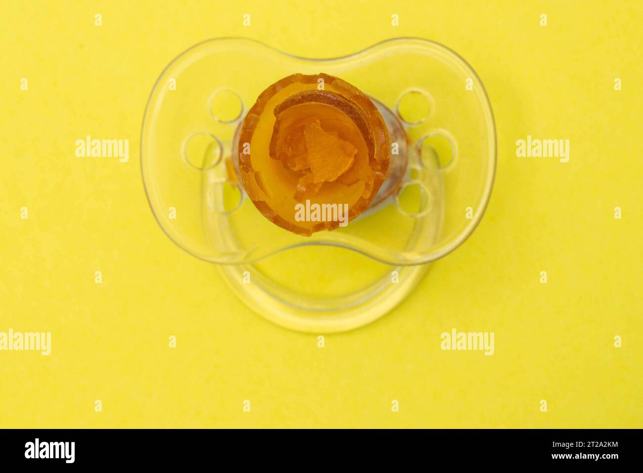 A chewed baby pacifier on a yellow background. Concept of teething in ...