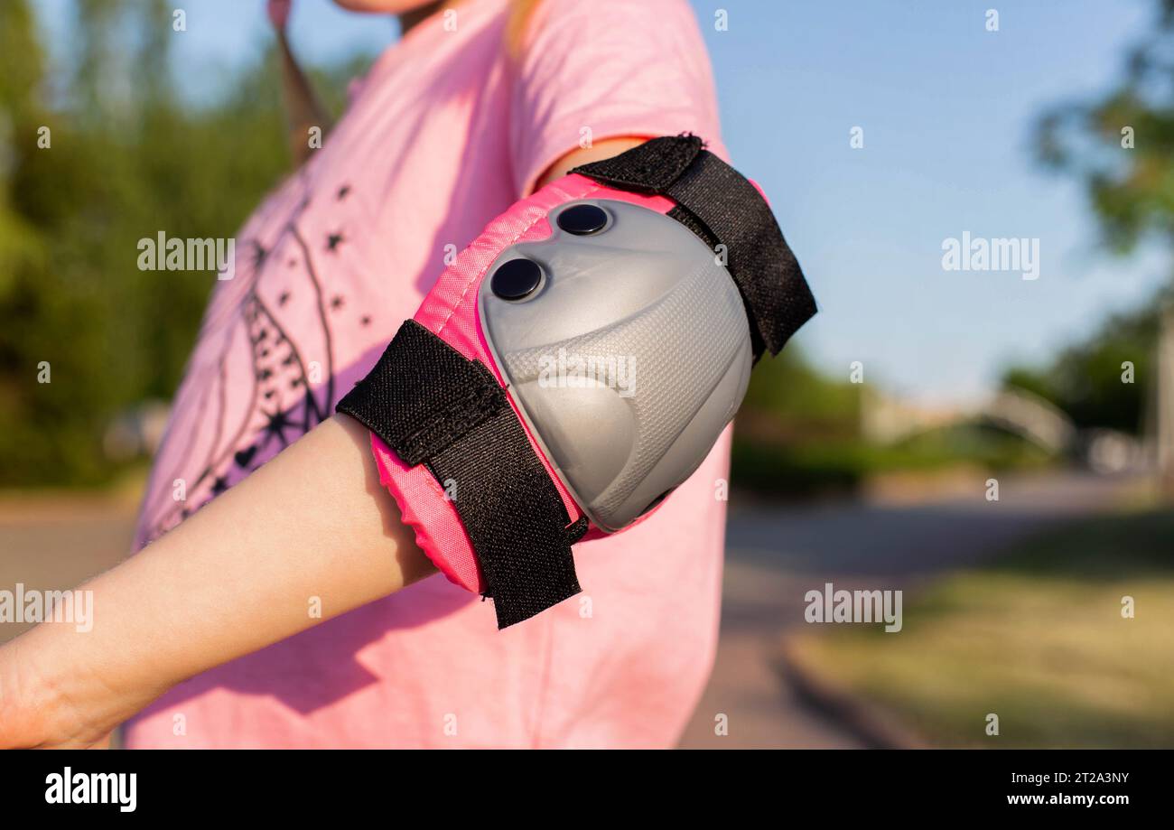 pink children's protection on the elbows of a girl who rides a scooter. Protection against falls ...