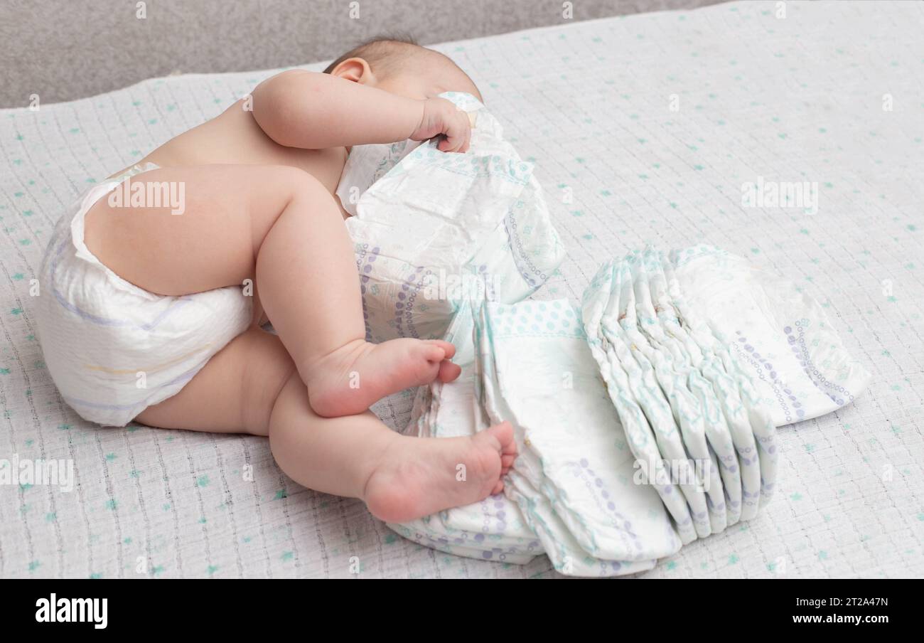 A little baby boy in a diaper lies on a white background and plays with ...