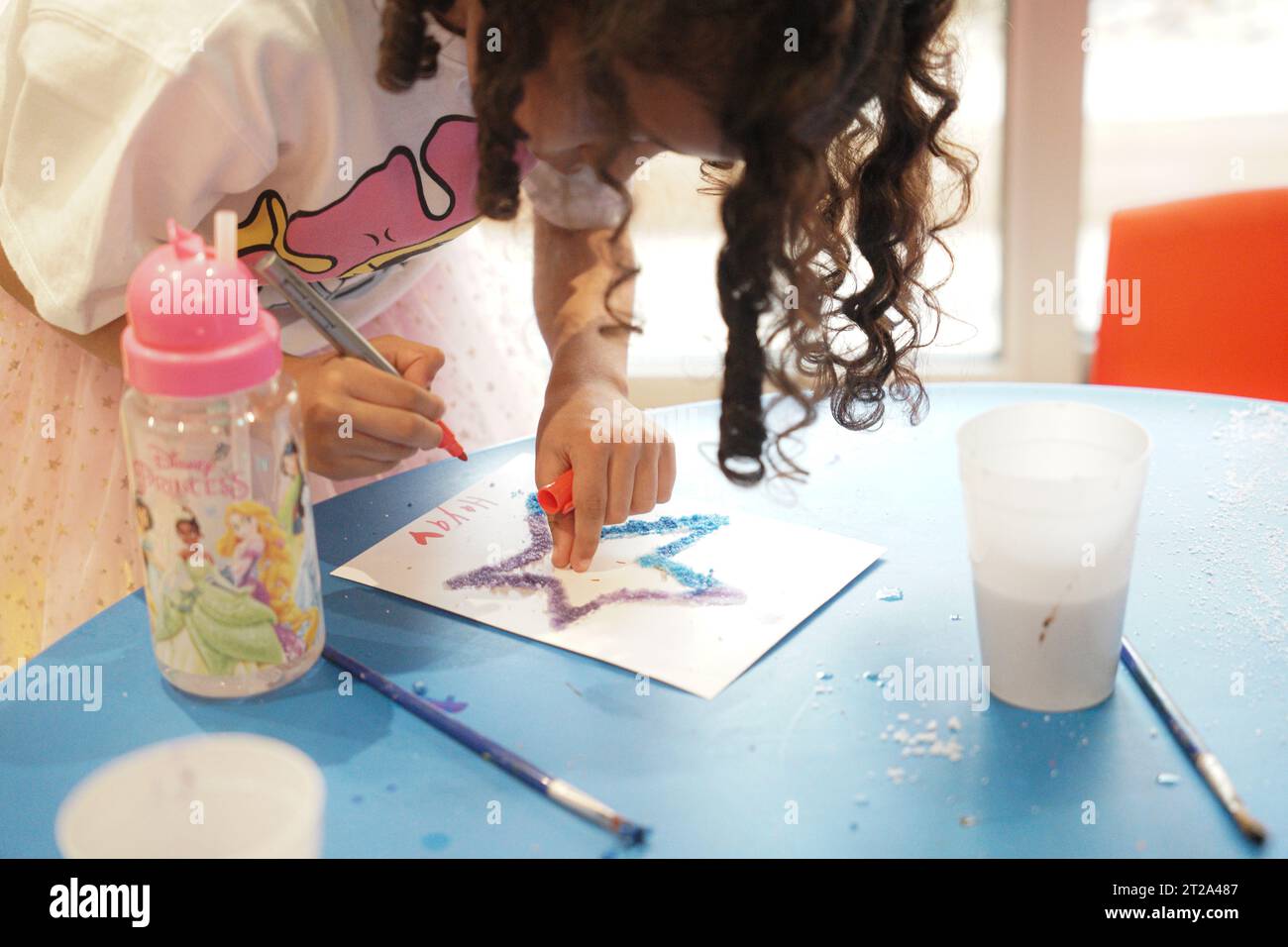 little kid coloring with salt and paint technique. girl at school doing ...