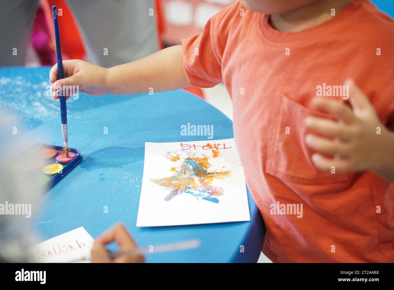 little toddler colouring with salt and paint technique. boy at school ...