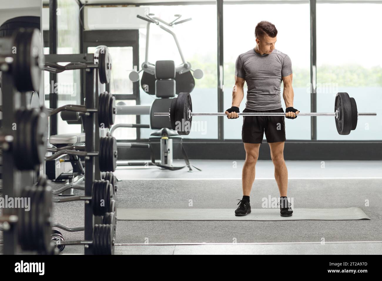 Full length shot of a young fit guy lifting weights at a gym Stock ...