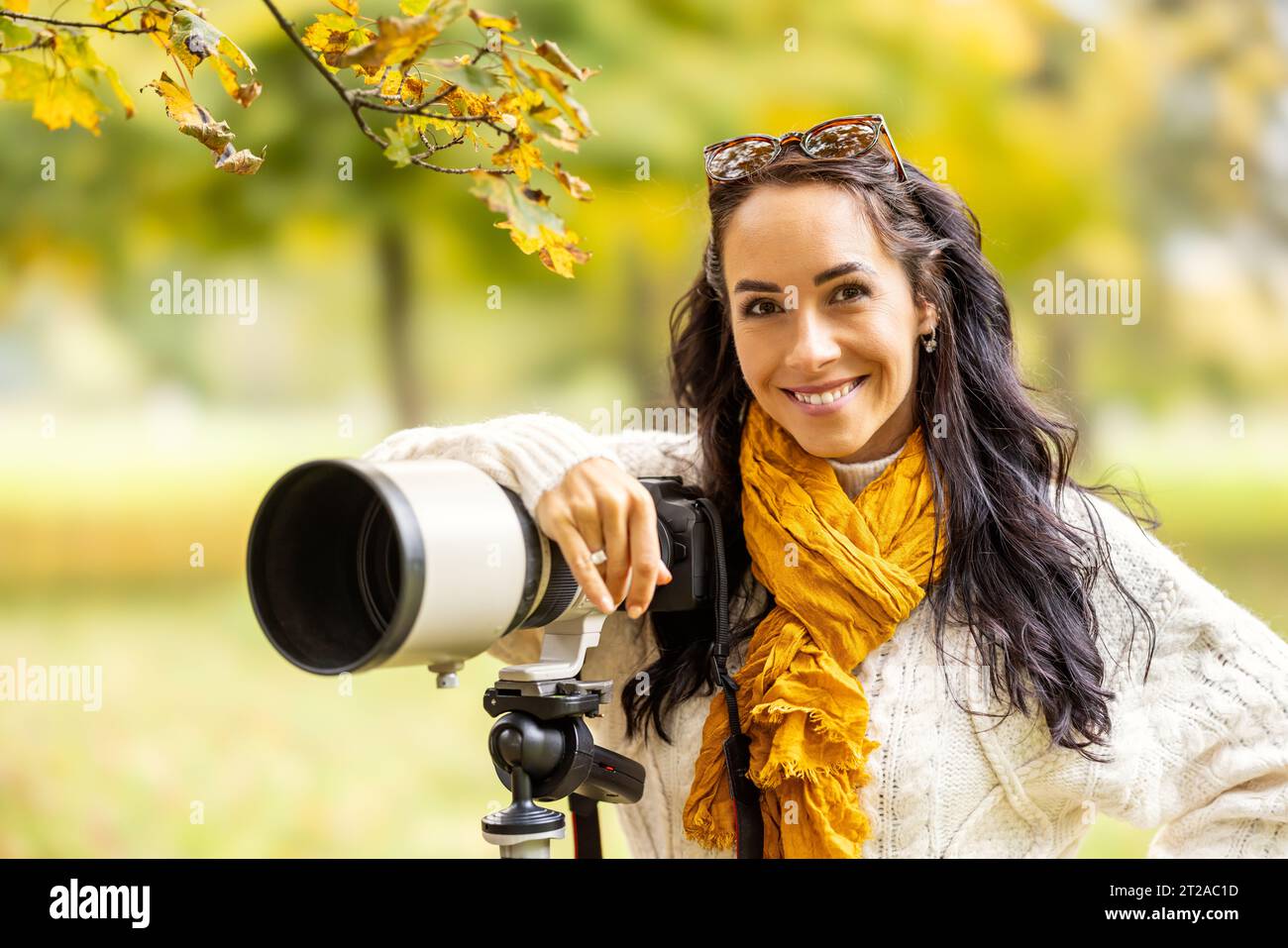 A professional female photographer stands next to her camera, taking ...
