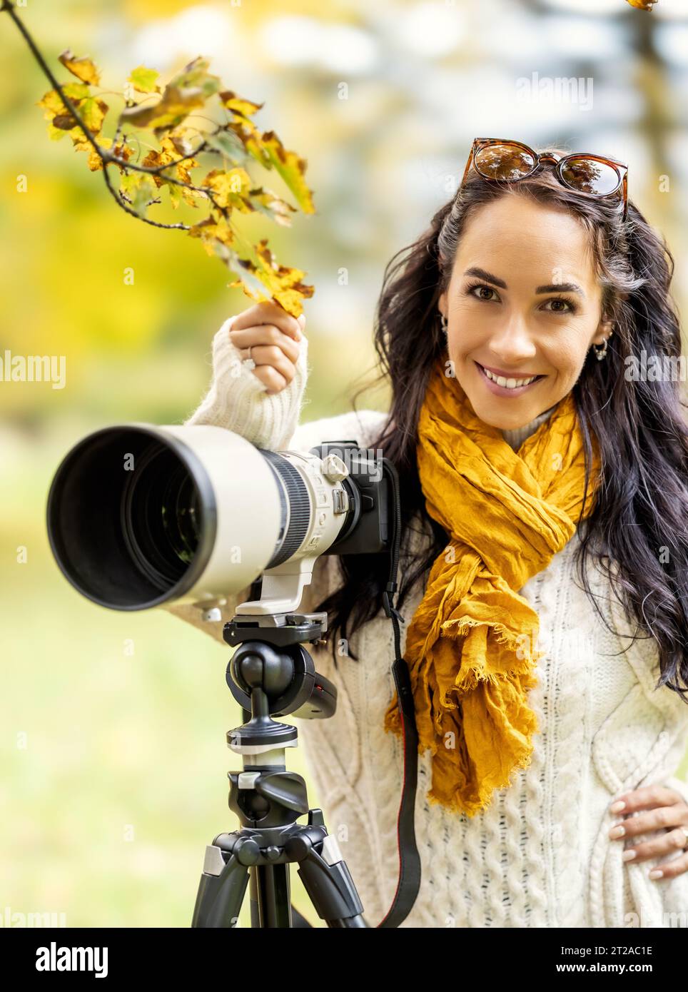 A professional female photographer stands next to her camera, taking ...