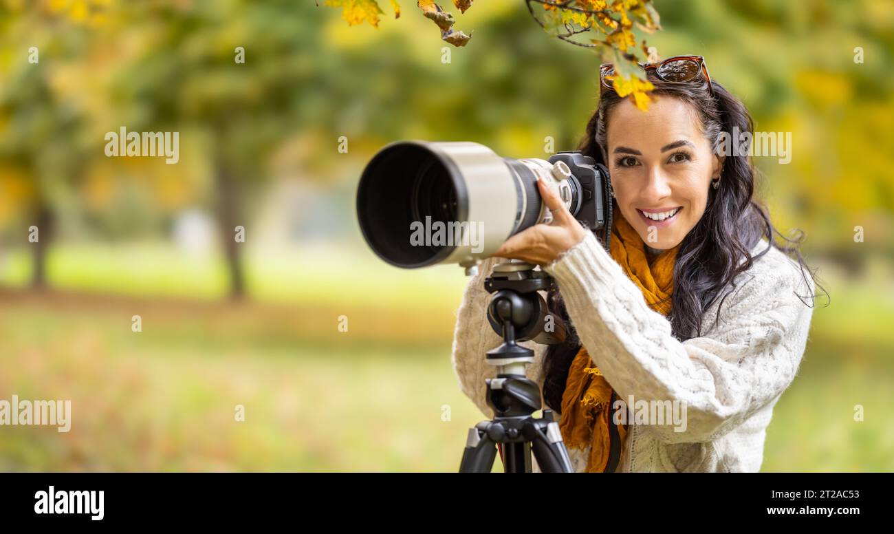 A satisfied photographer is standing behind her camera placed on a ...