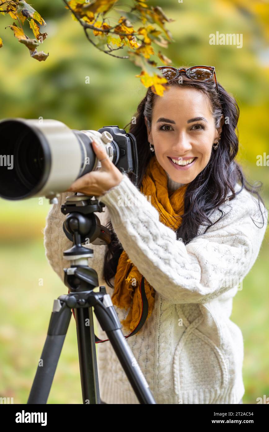 A professional female photographer stands next to her camera, taking ...