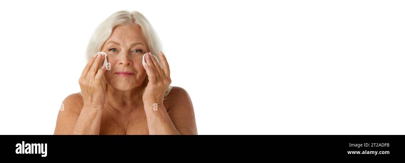 Beautiful senior woman with wrinkles, taking off makeup with cotton ...