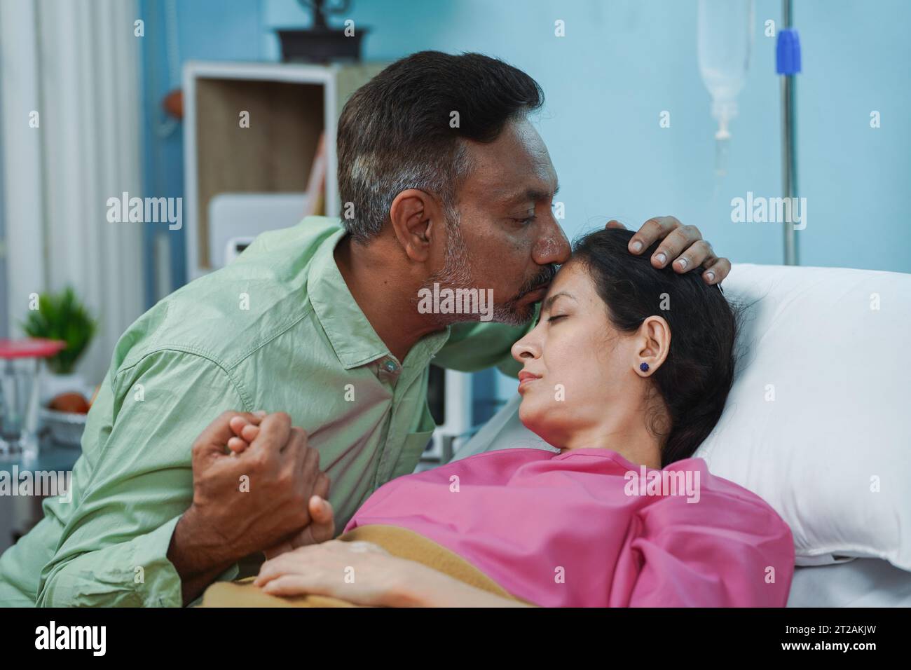 loving supportive husband comforts his wife during her hospital stay by ...