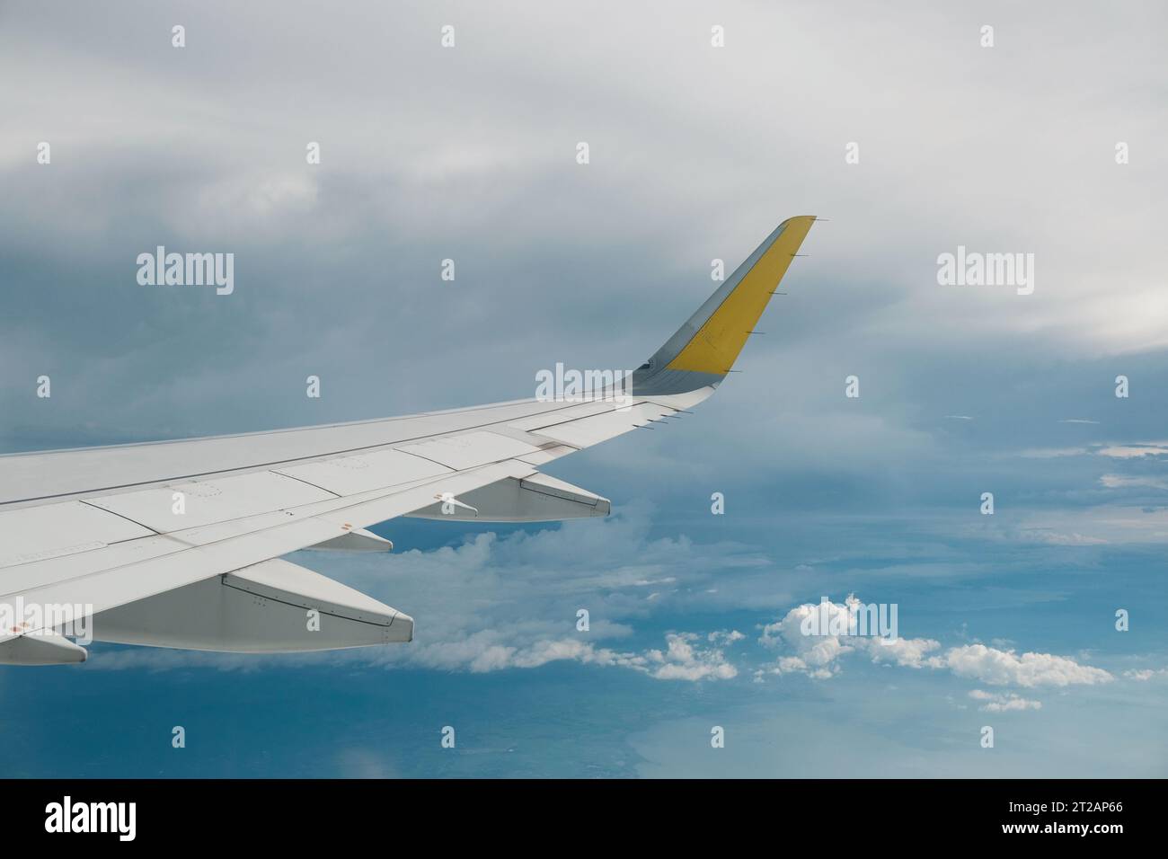 View of right wing from window of airplane flying up in the air. Clouds ...