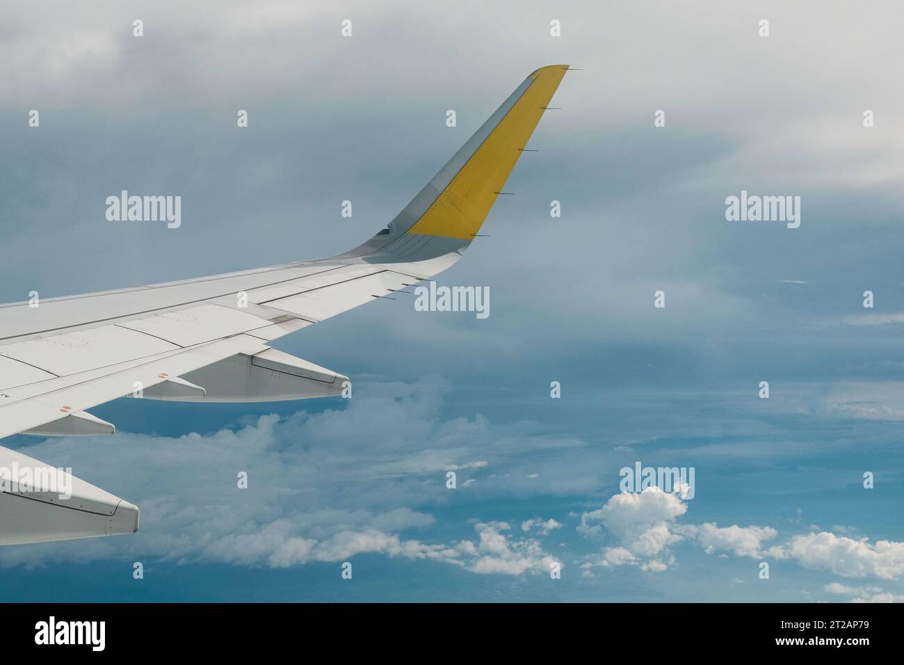 View of right wing from window of airplane flying up in the air. Clouds ...