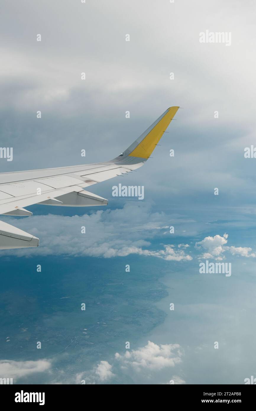 View of right wing from window of airplane flying up in the air. Clouds ...