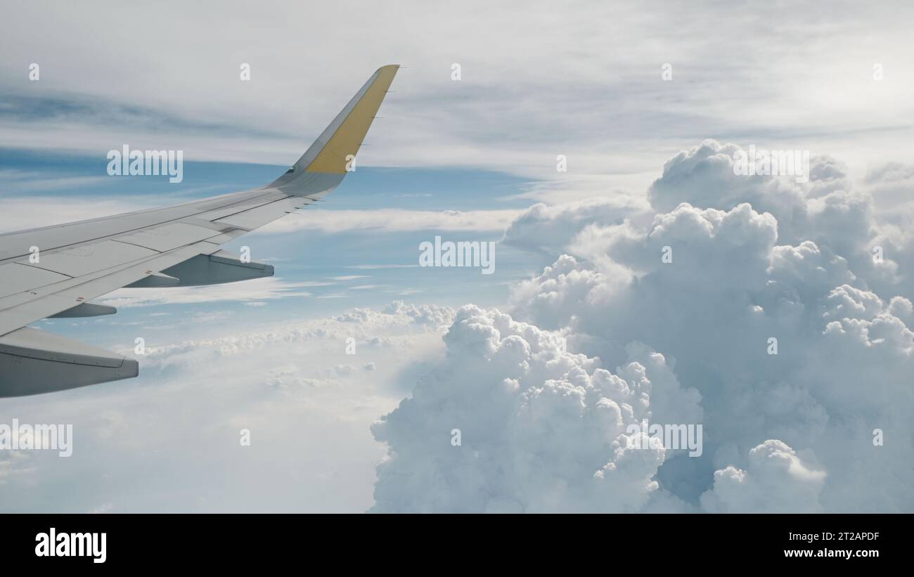 View of right wing from window of airplane flying up in the air. Clouds ...