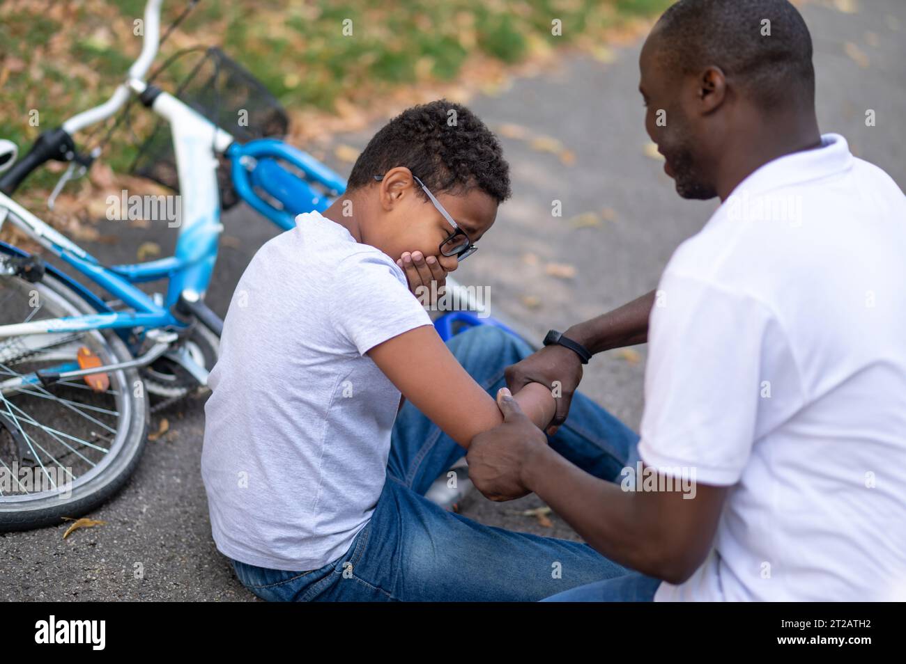 Dad helping his son after falling donw from the bike Stock Photo - Alamy