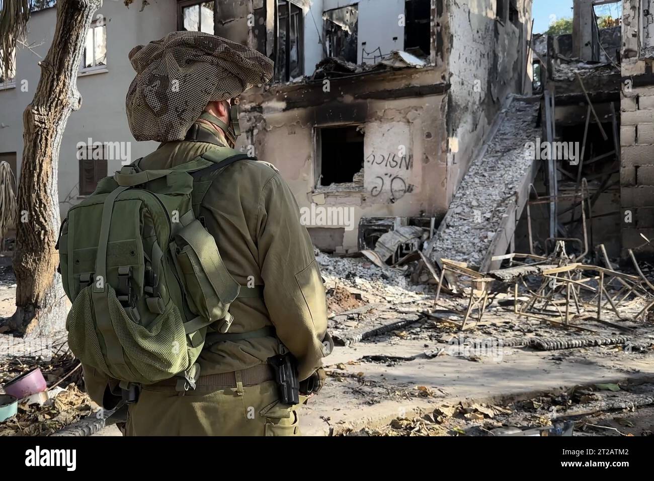 An Israeli soldier stands guard next to houses damaged in a battle ...