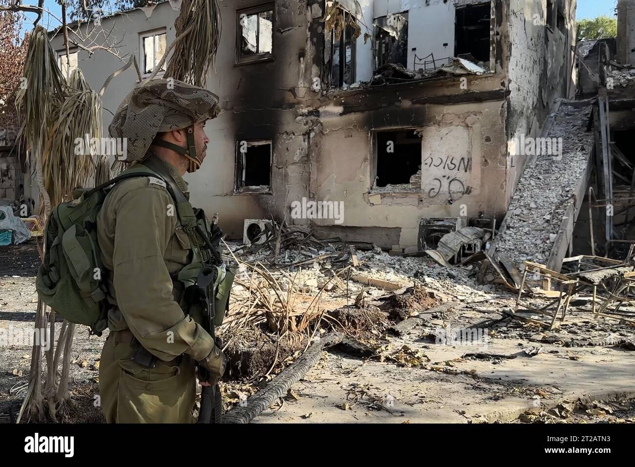 An Israeli soldier stands guard next to houses damaged in a battle ...