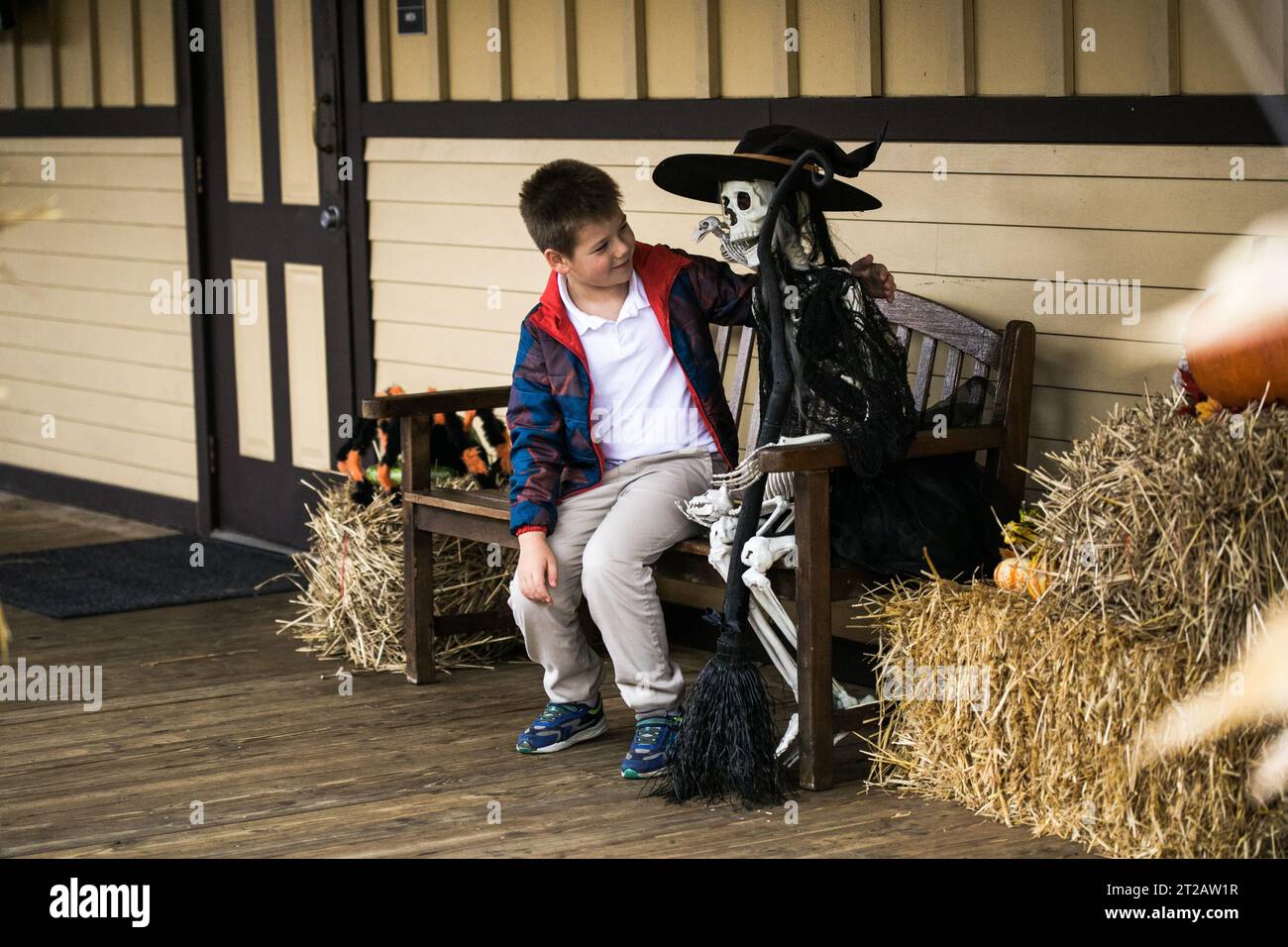 Smiling boy hugging to skeleton while sitting against door during ...