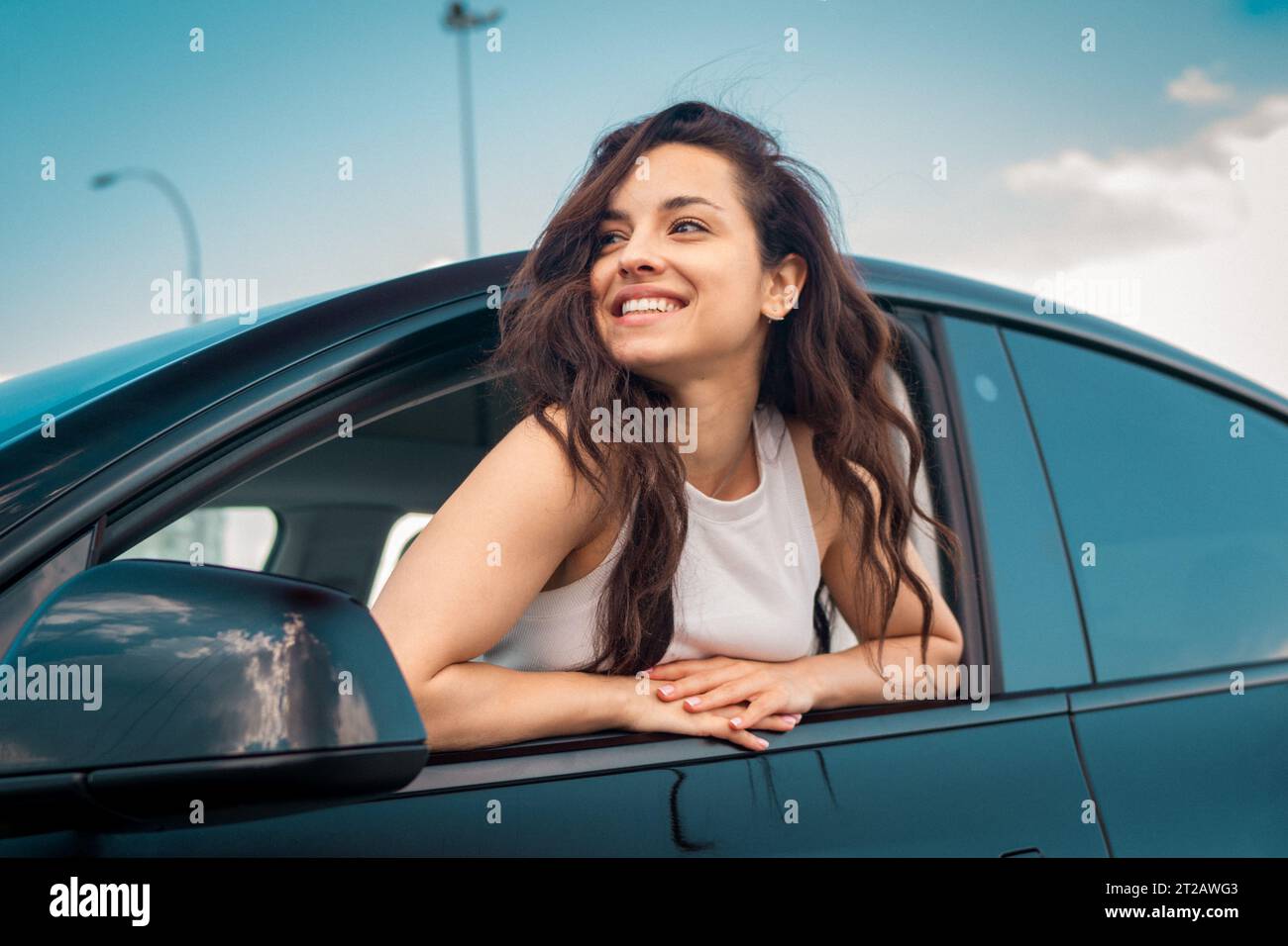 Smiling pretty lady sticking her head out the side view window while ...