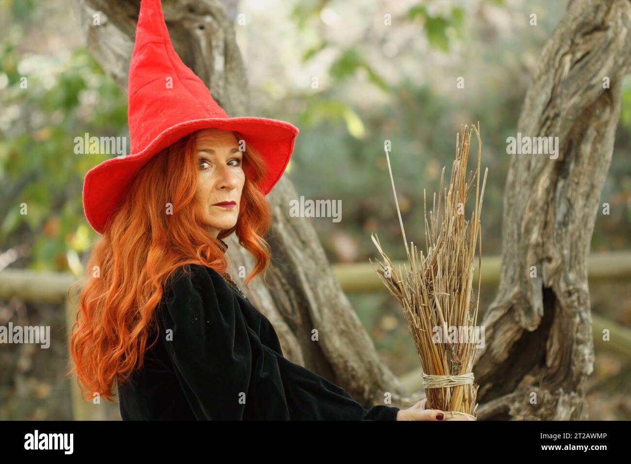 Redhead witch with red hat and broom looking at camera in the preventory of Alcoi, Spain Stock ...